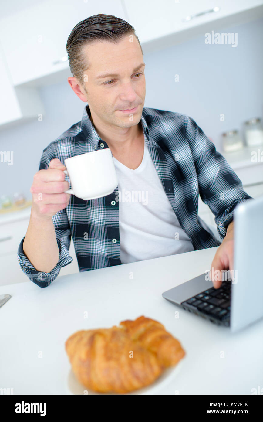 man drinking coffee while using laptop at home Stock Photo - Alamy
