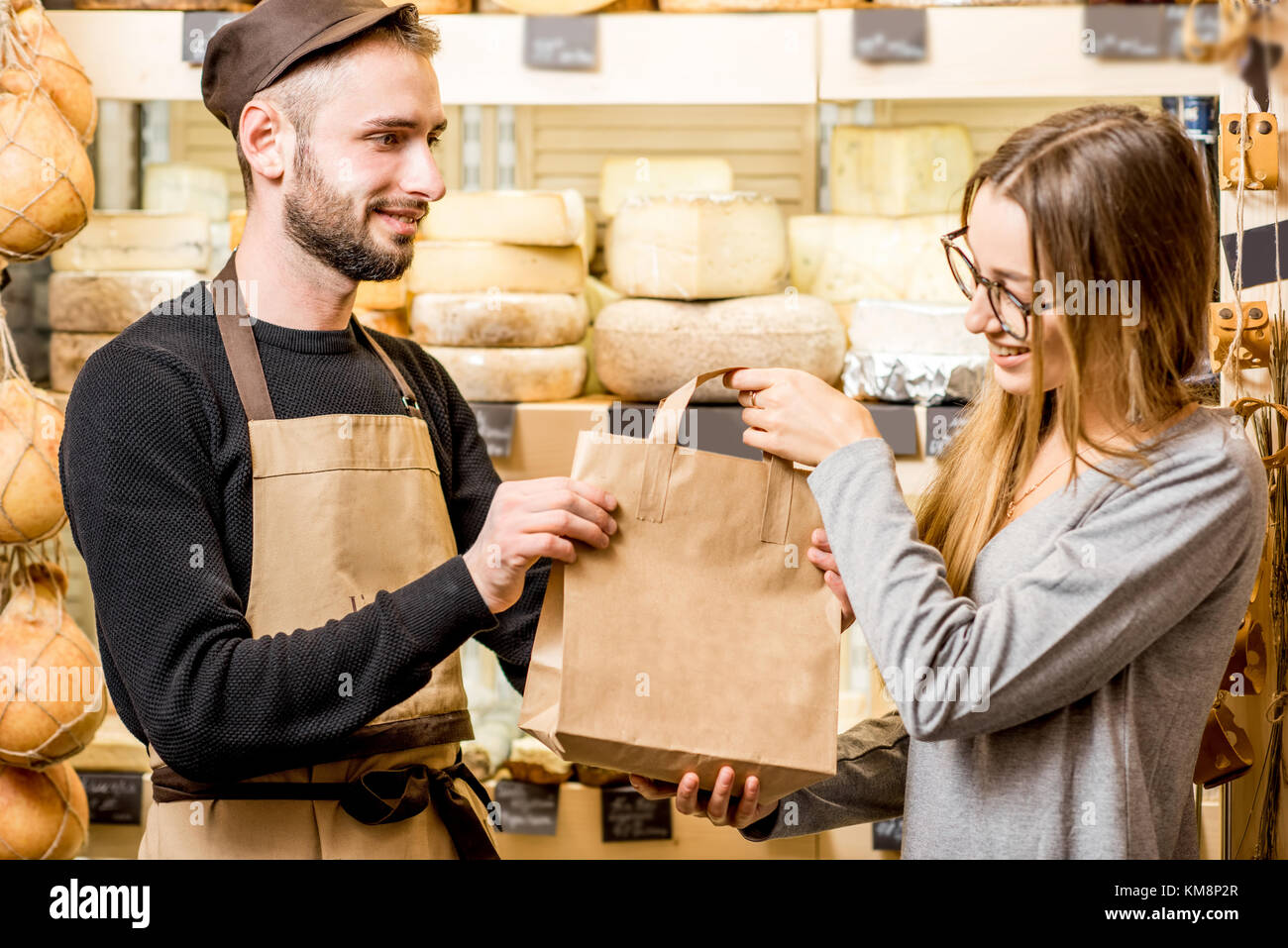 Salesman packing shopping bag with goods and giving to the woman ...