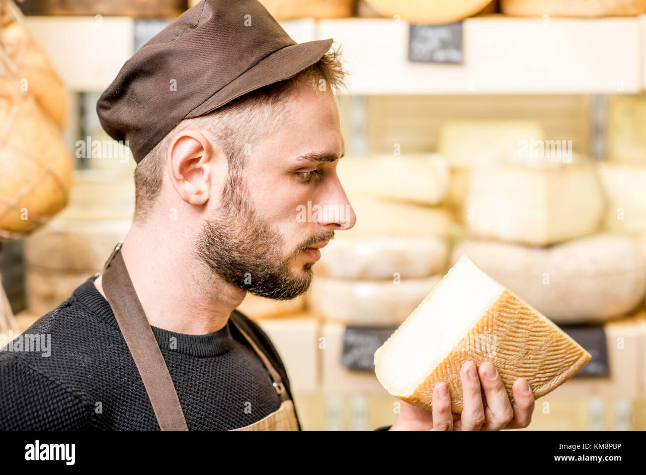 Portrait of a handsome cheese seller in uniform smelling seasoned ...
