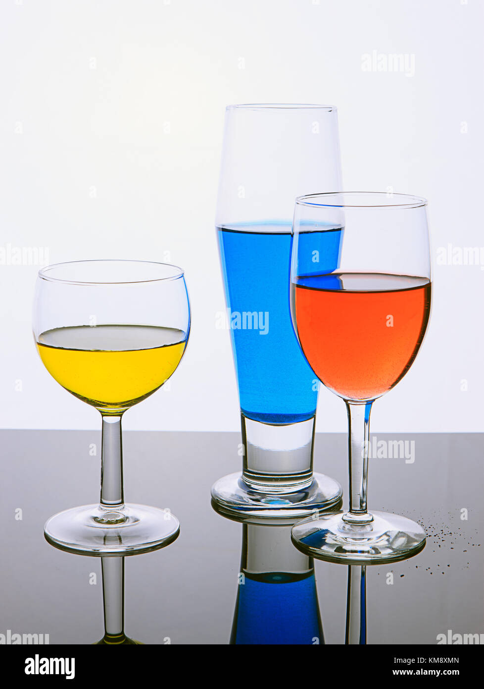 Various glasses that are filled with colored liquid for an abstract ...