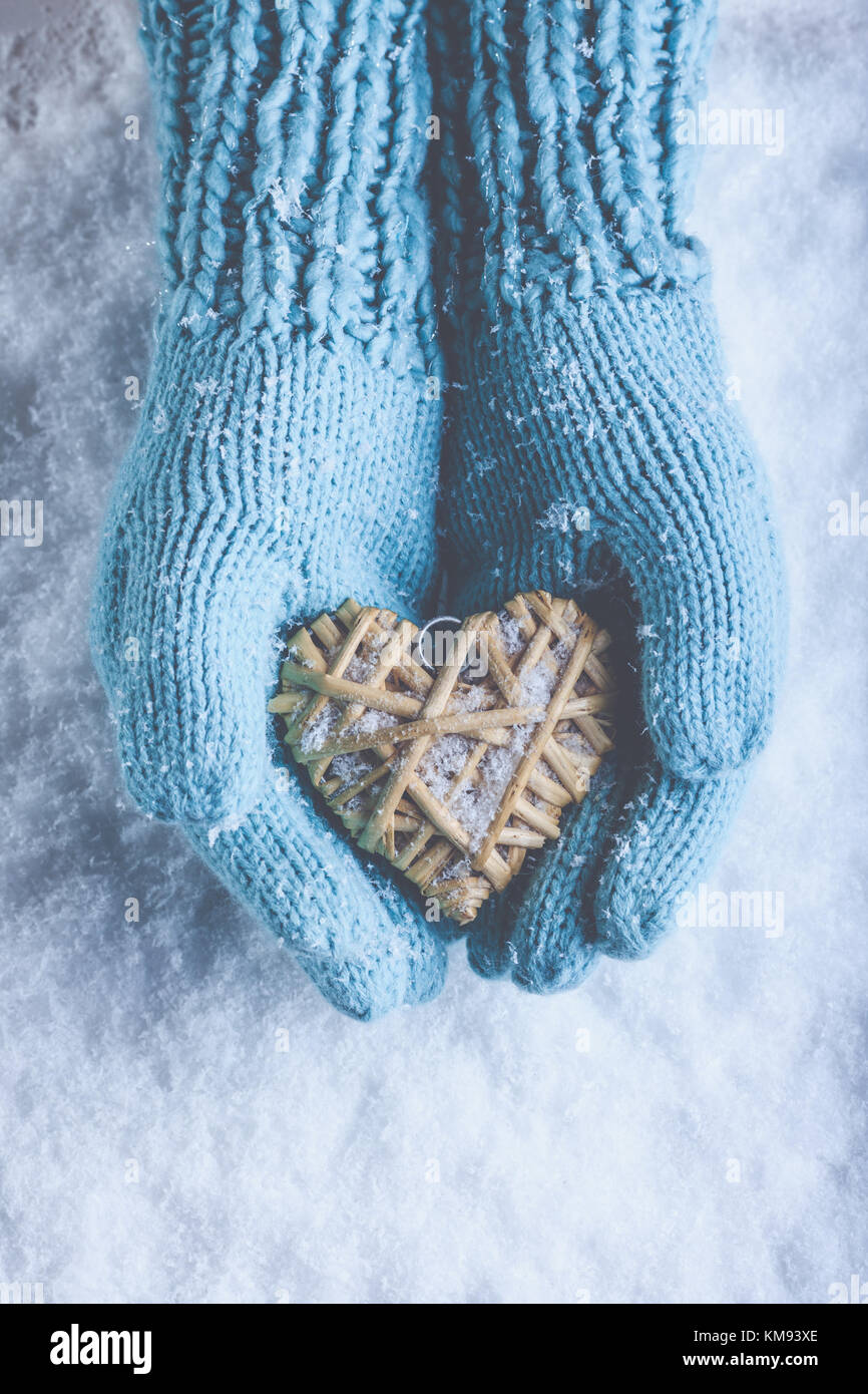 Female hands in light teal knitted mittens with entwined beige flaxen ...