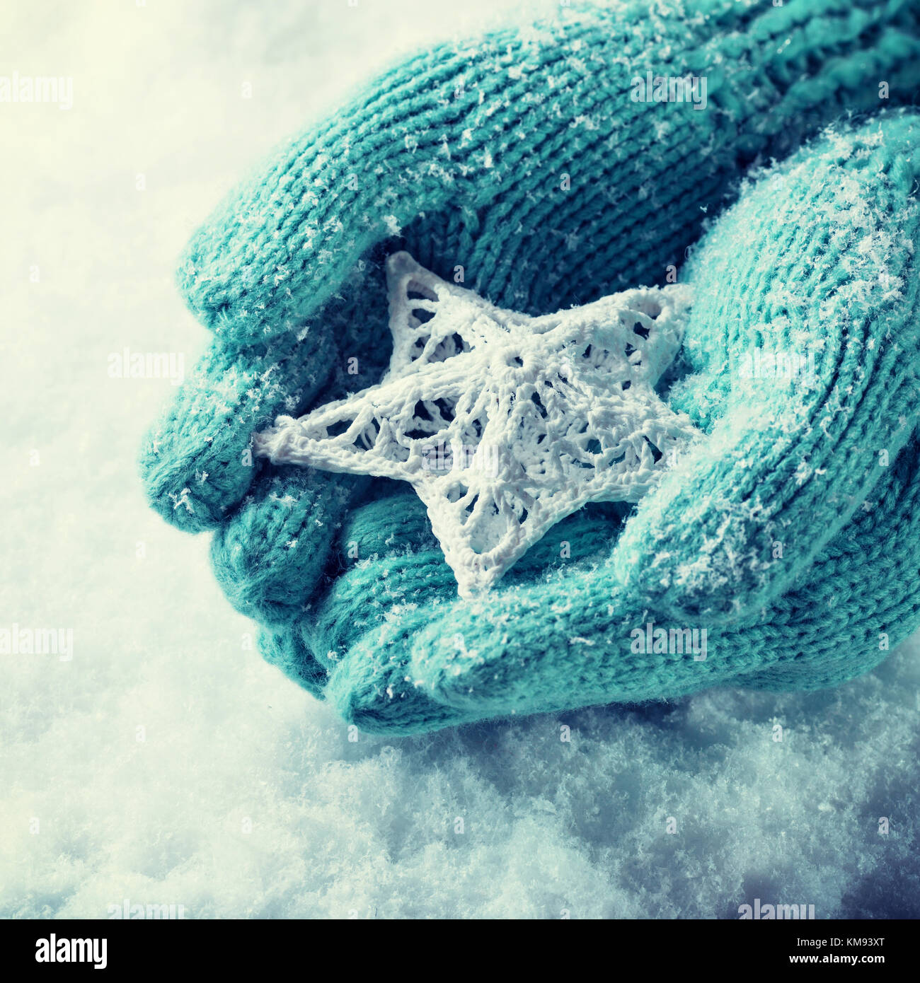 Female hands in light teal knitted mittens with entwined white star on ...