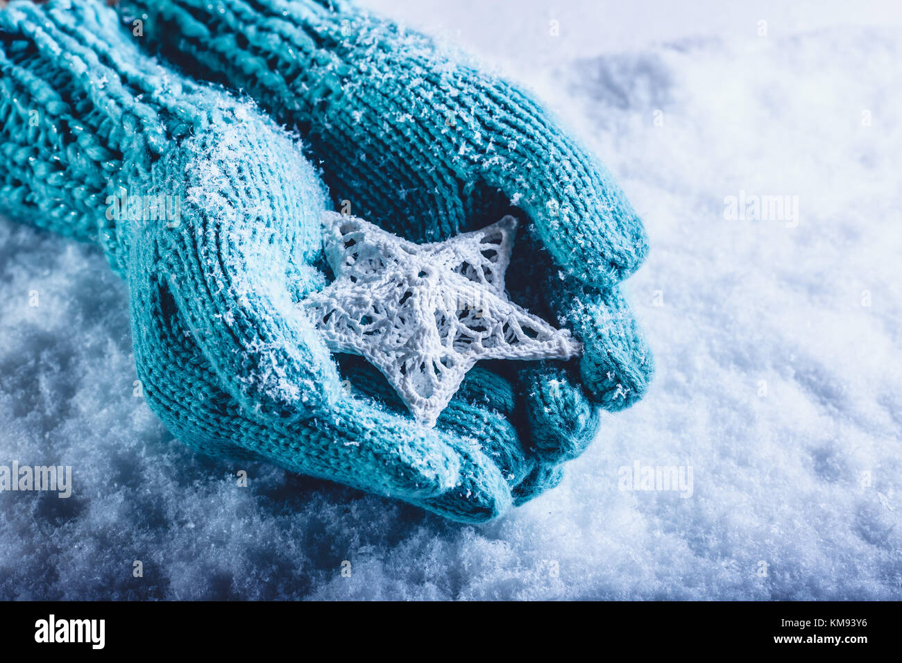 Female hands in light teal knitted mittens with entwined white star on ...