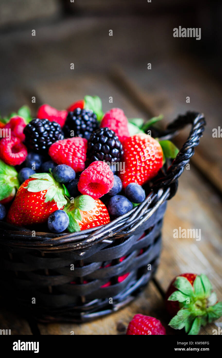 Mix Of Fresh Berries In A Basket On Rustic Wooden Background Stock ...