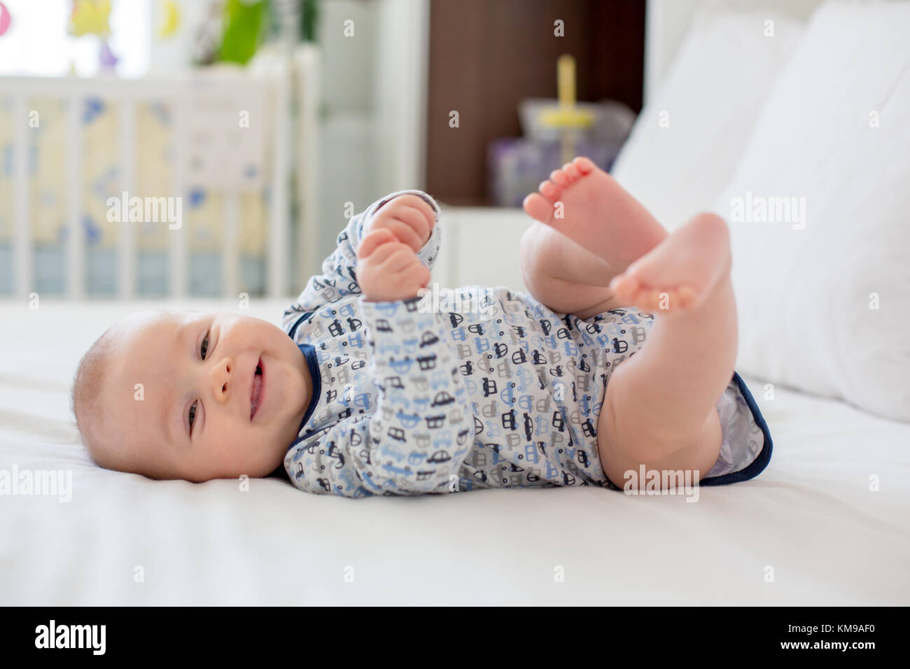 Cute little smiling newborn baby boy, playing in bed in the morning ...