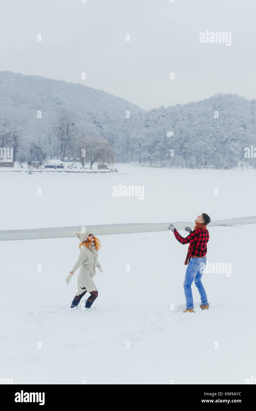 Funny walk of a loving couple playing snow balls on the meadow covered ...