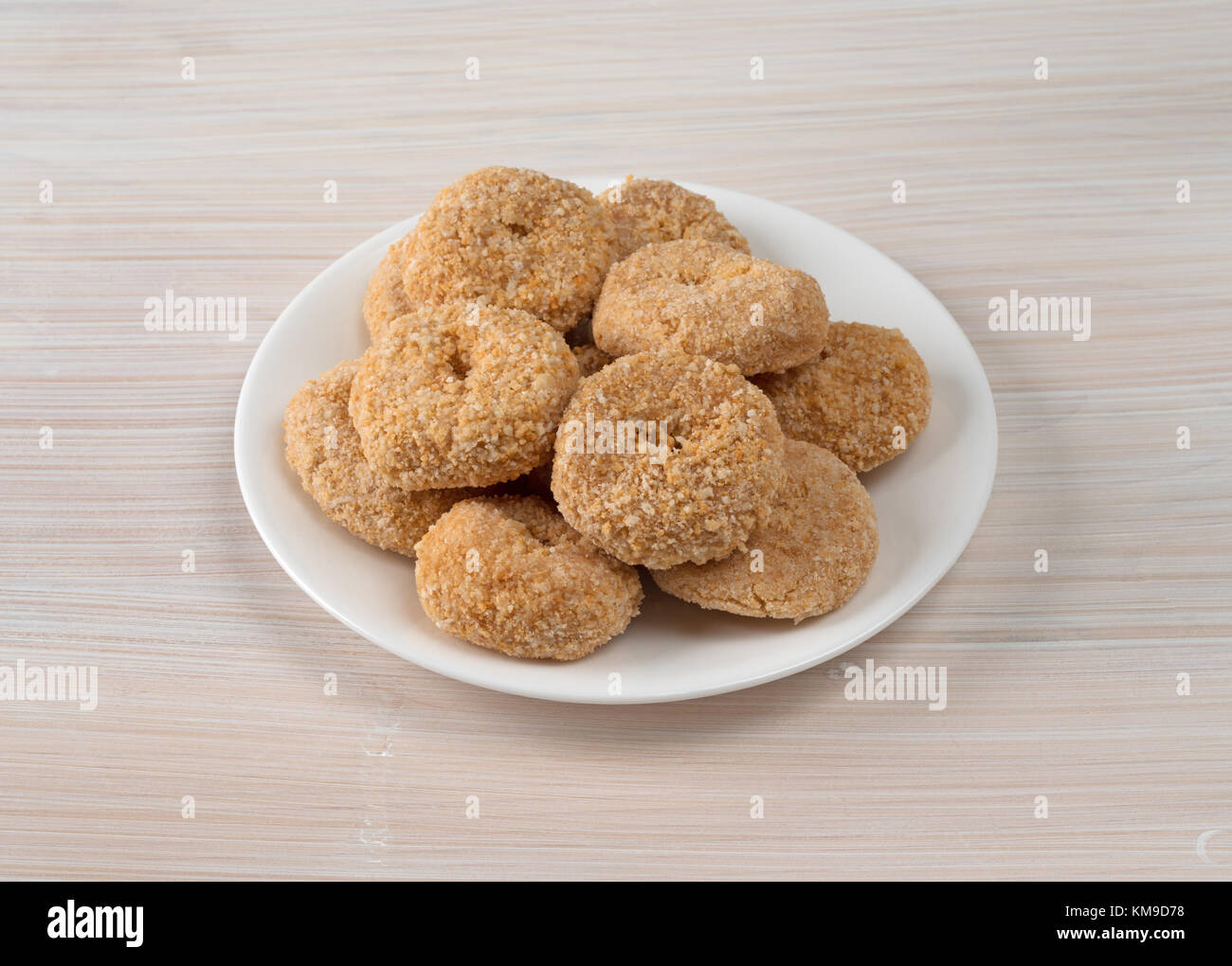 Several small bite size caramel flake donuts on a white plate atop a ...