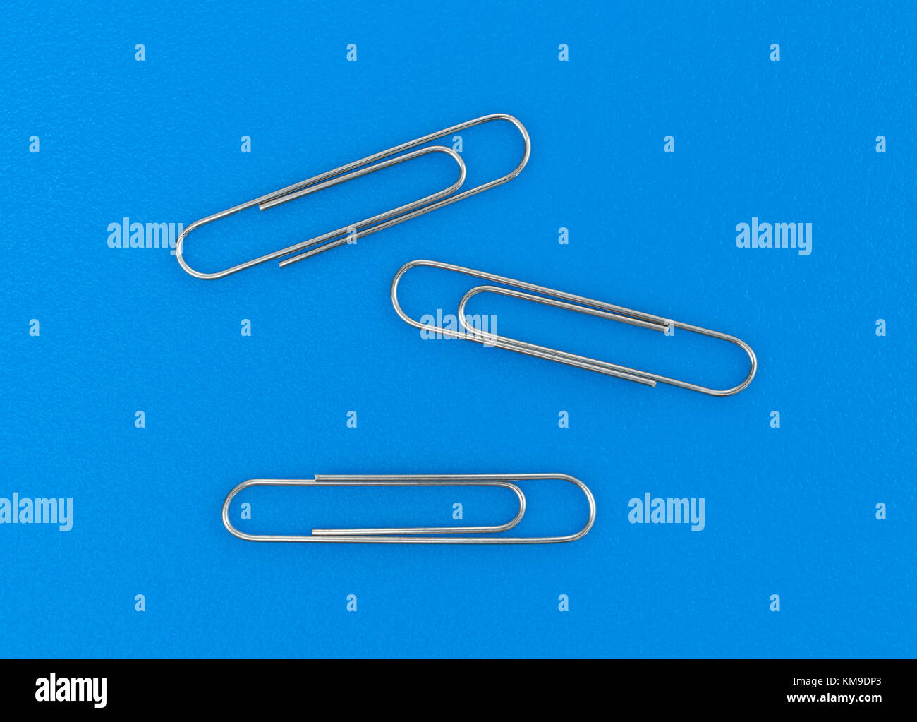 Three metal paper clips on a blue plastic background Stock Photo - Alamy