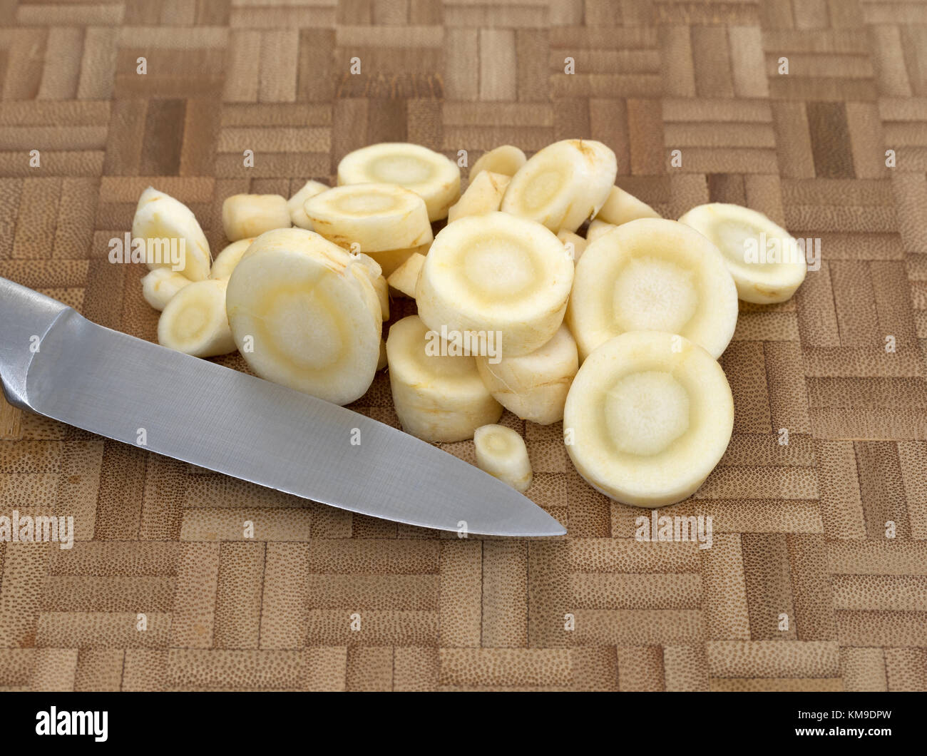 Portion of parsnip slices plus a knife on a wood cutting board Stock ...