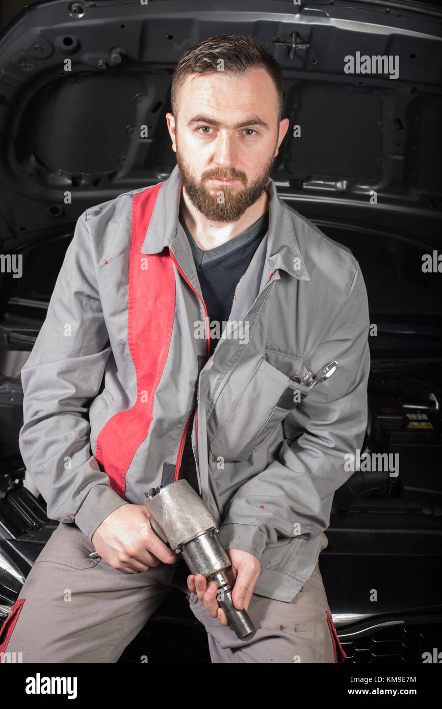 Portrait of a mechanic holding a tire pistol Stock Photo - Alamy