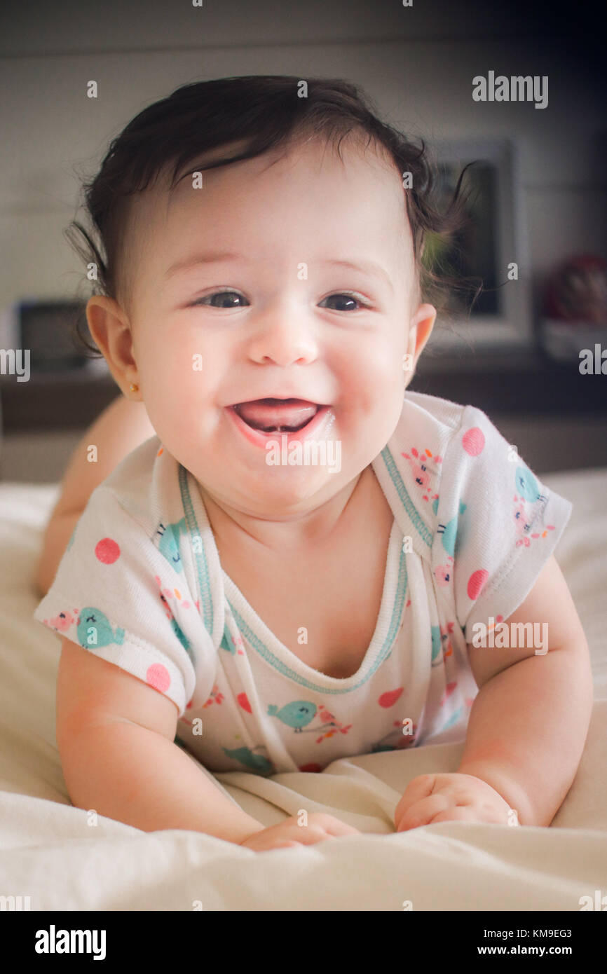 Portrait of a smiling baby girl lying on her front Stock Photo - Alamy