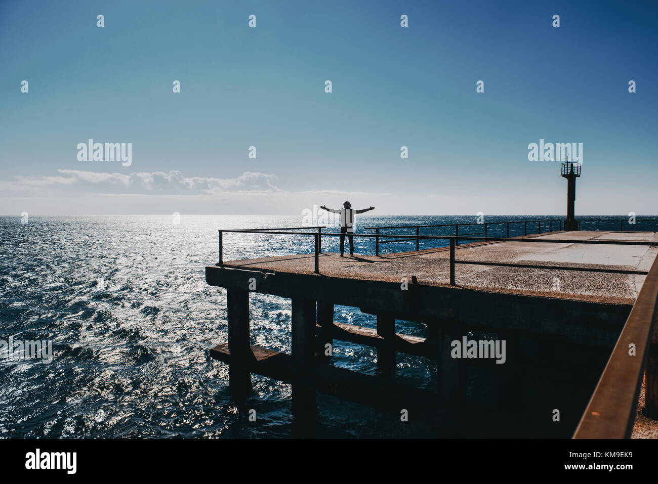 Man standing on a pier with his arms outstretched Stock Photo - Alamy