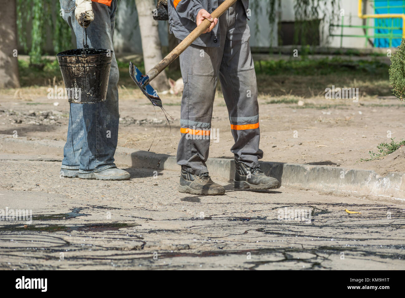 Road repair. Work details, workers pour resin road surface to cover the ...