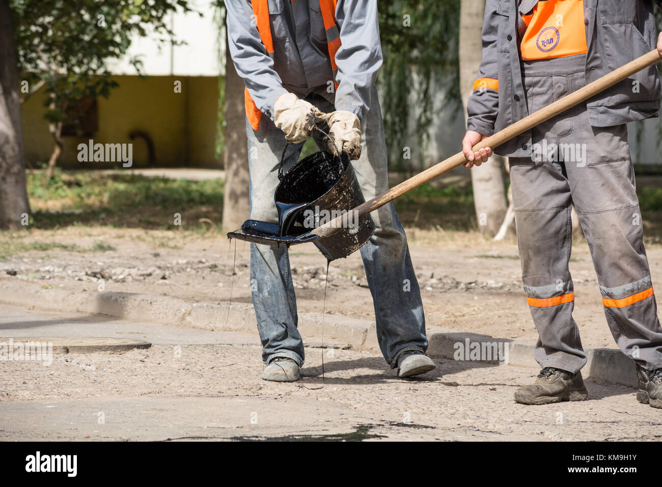 Road repair. Work details, workers pour resin road surface to cover the ...
