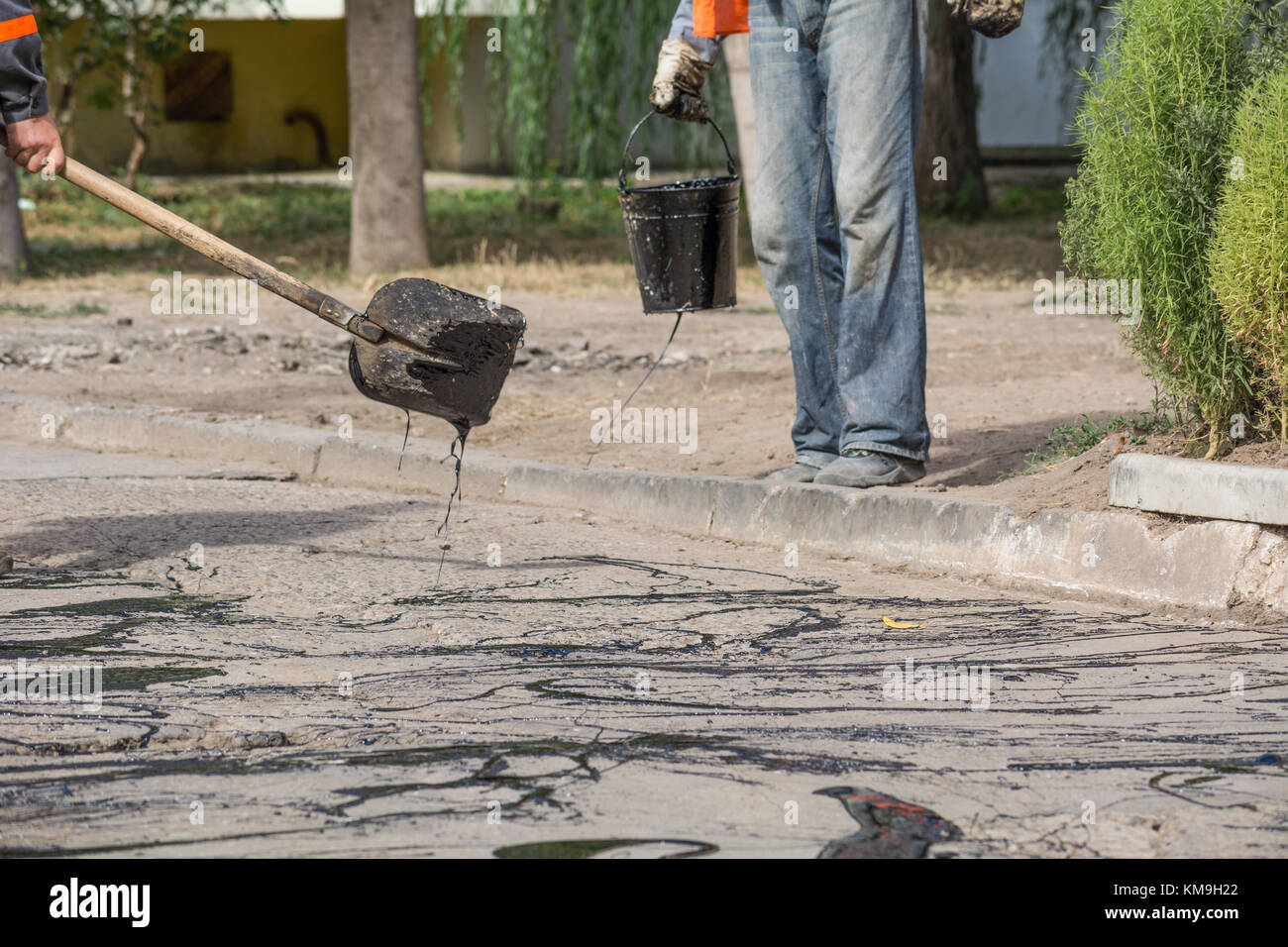 Road repair. Work details, workers pour resin road surface to cover the ...