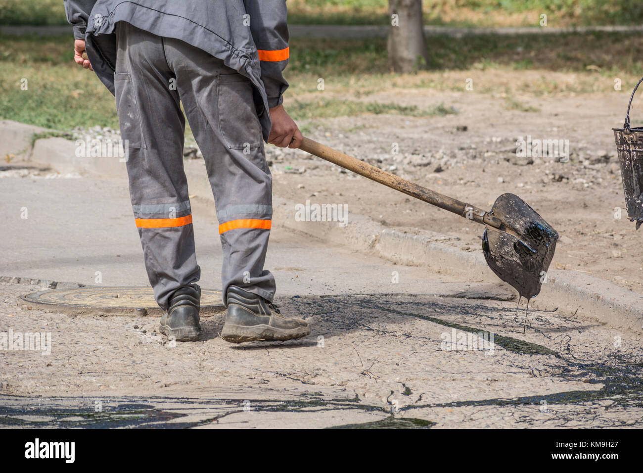 Road repair. Work details, workers pour resin road surface to cover the ...