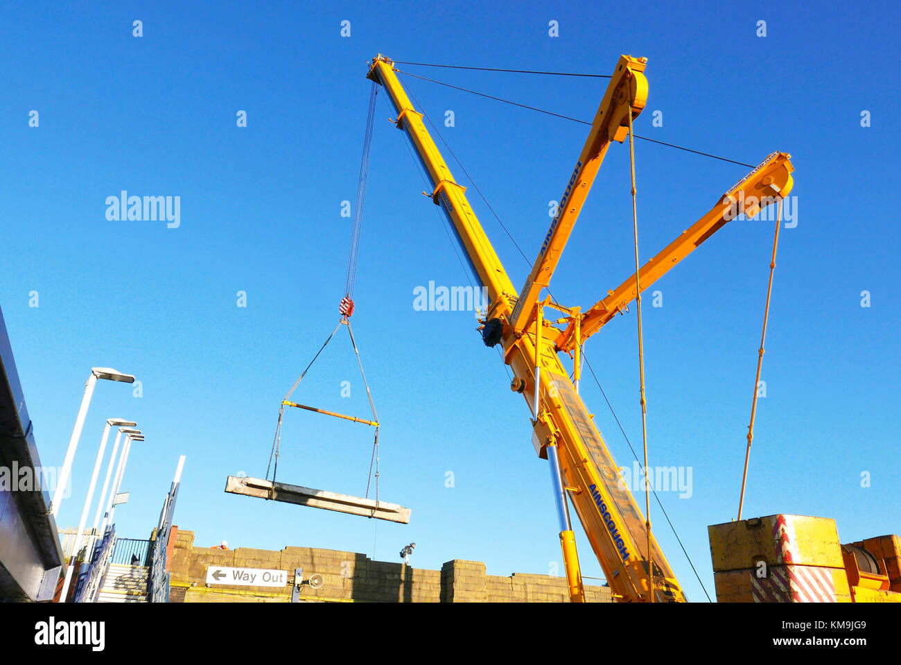 Giant yellow crane against blue sky working on railway bridge ...