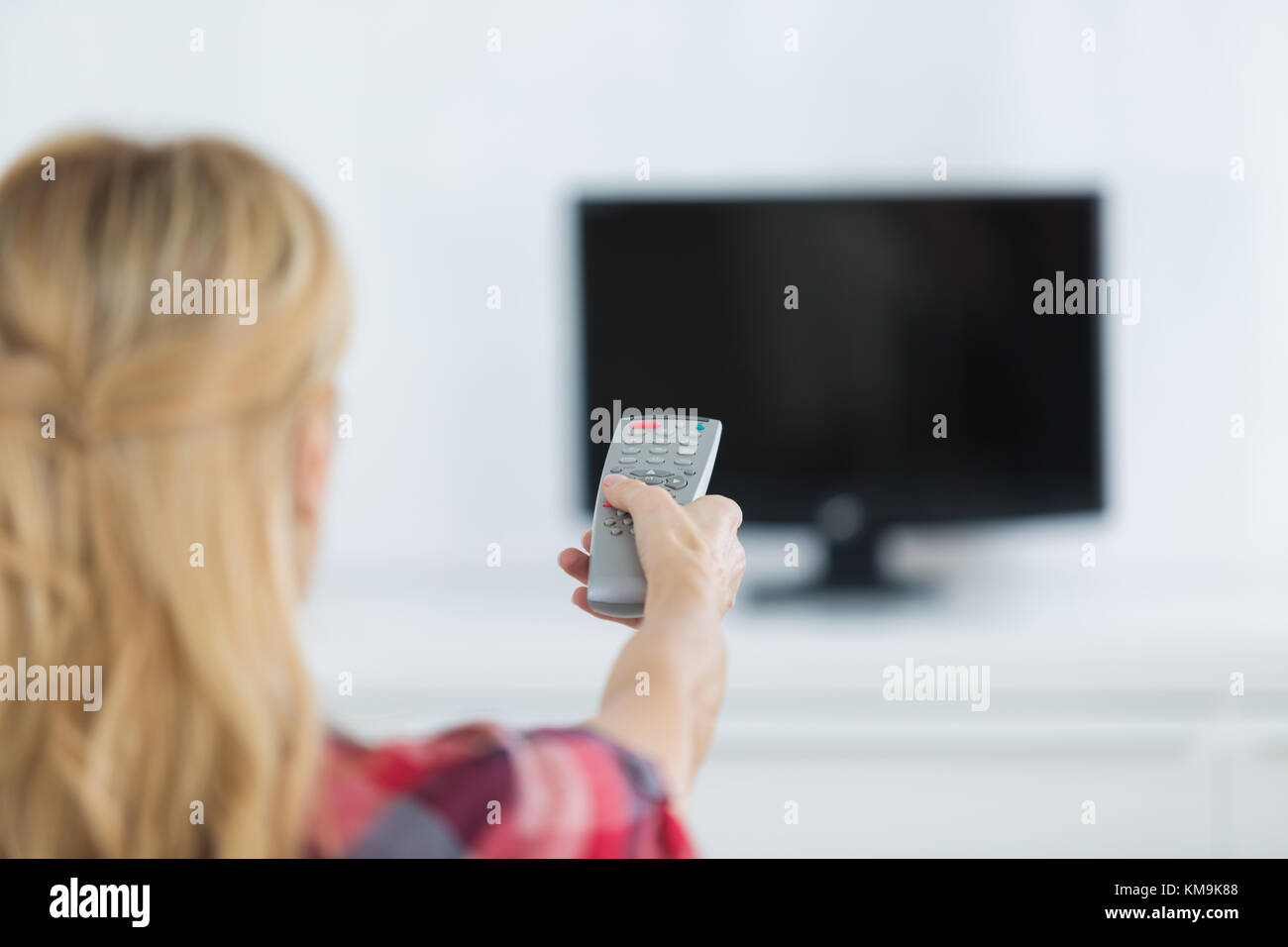 rear view of woman sitting on sofa holding tv remote Stock Photo - Alamy