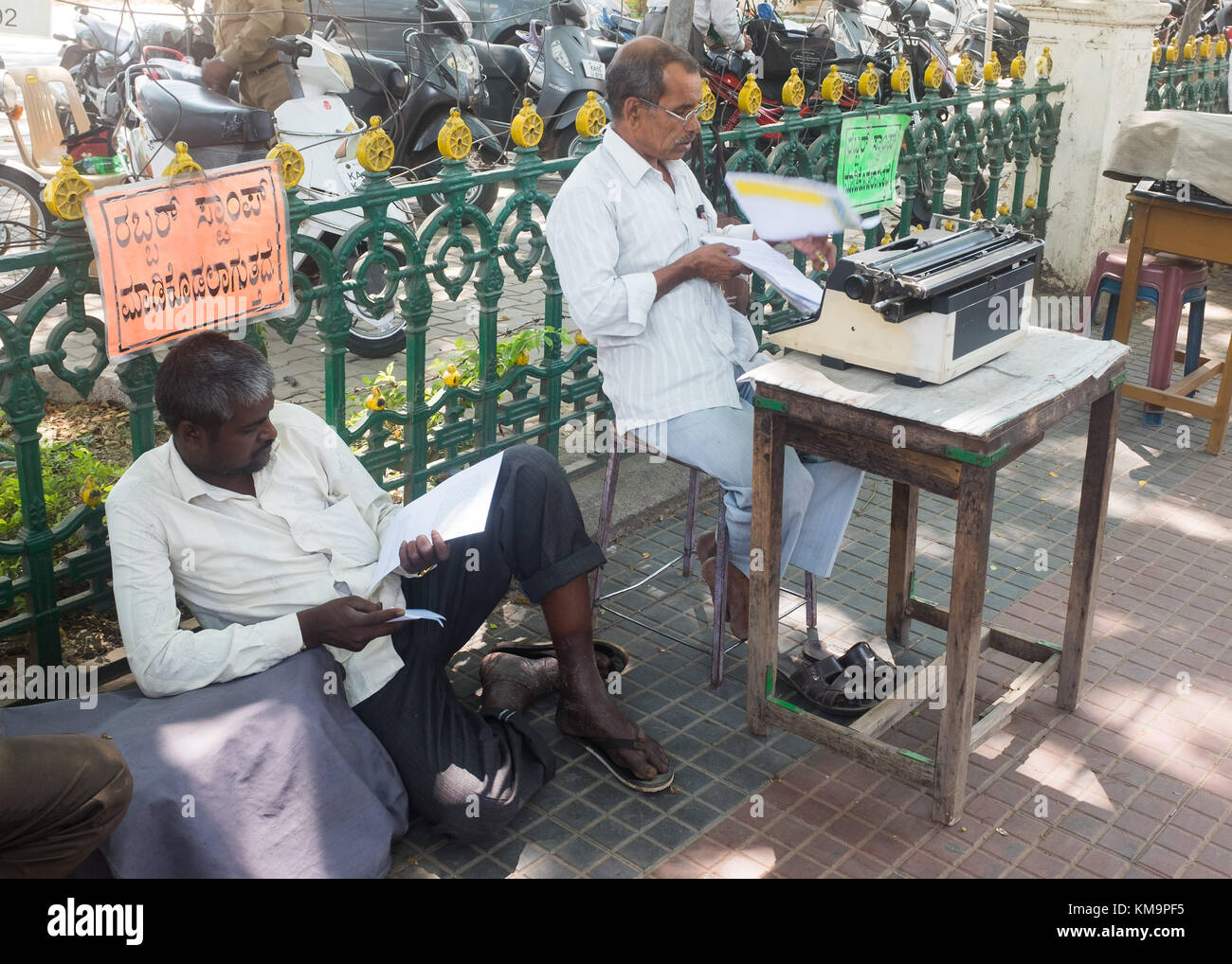 Street typist and customer going through their documents on footpath at ...