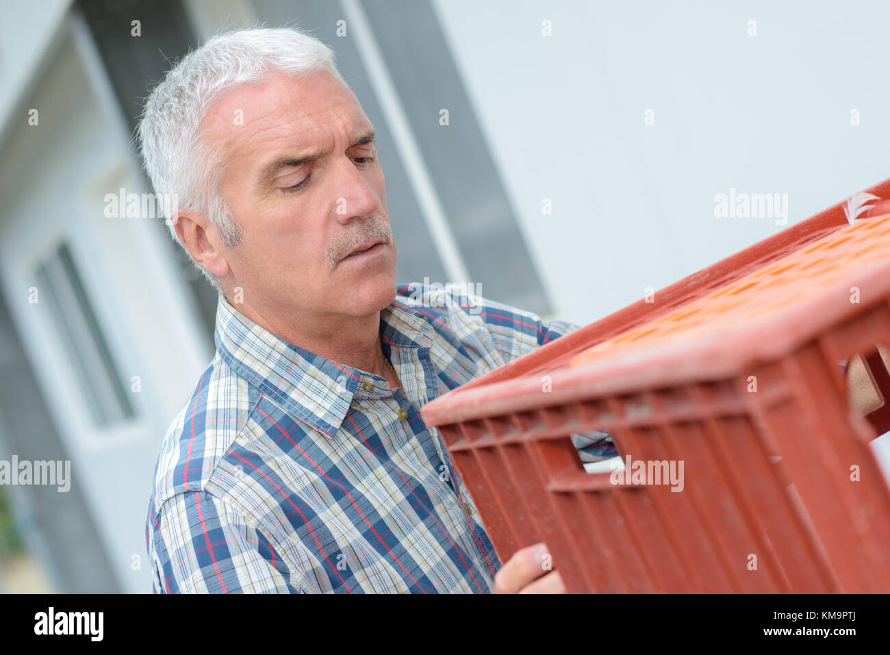 Man carrying plastic crate Stock Photo - Alamy