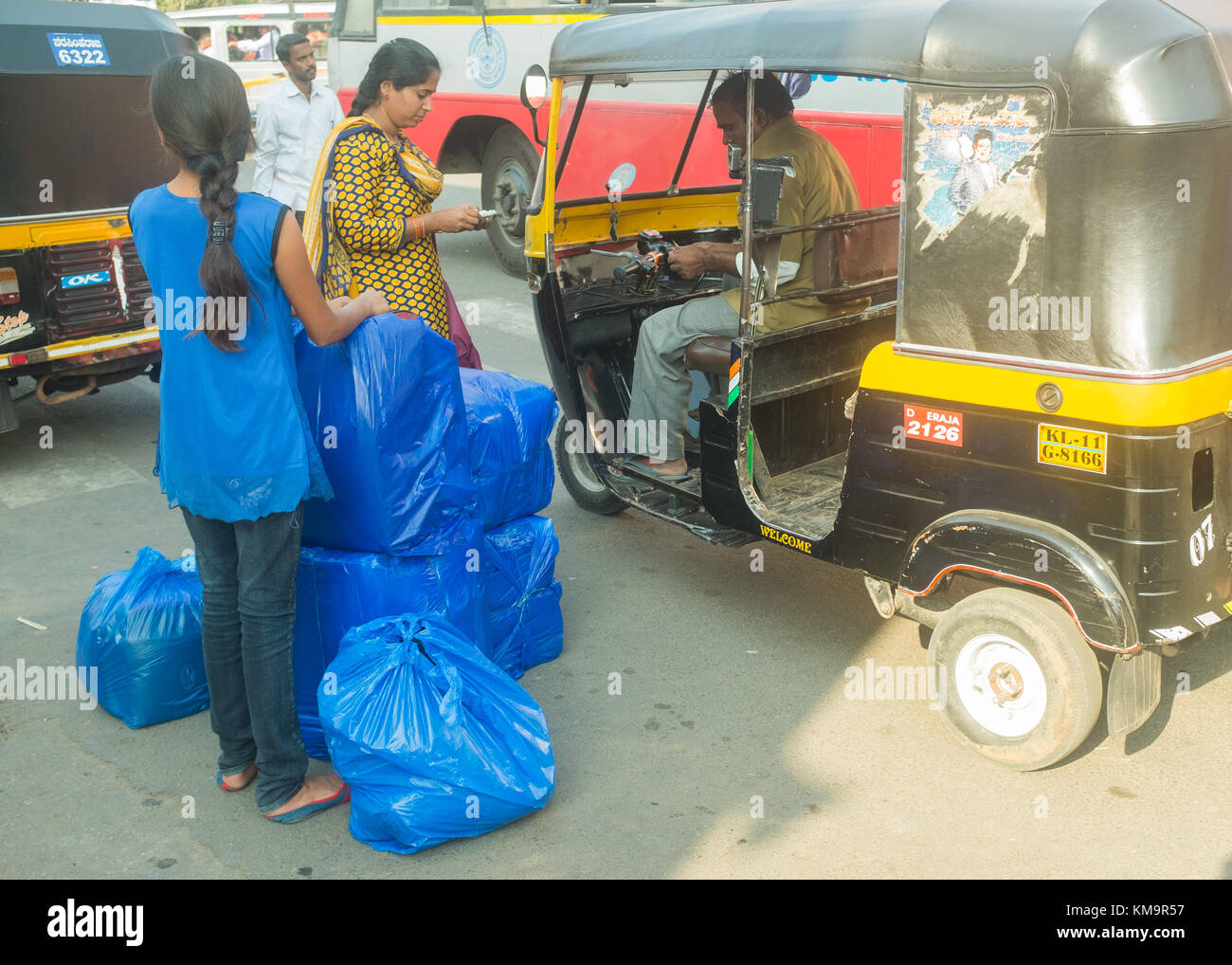Two women with lots of luggage paying auto rickshaw driver outside bus ...