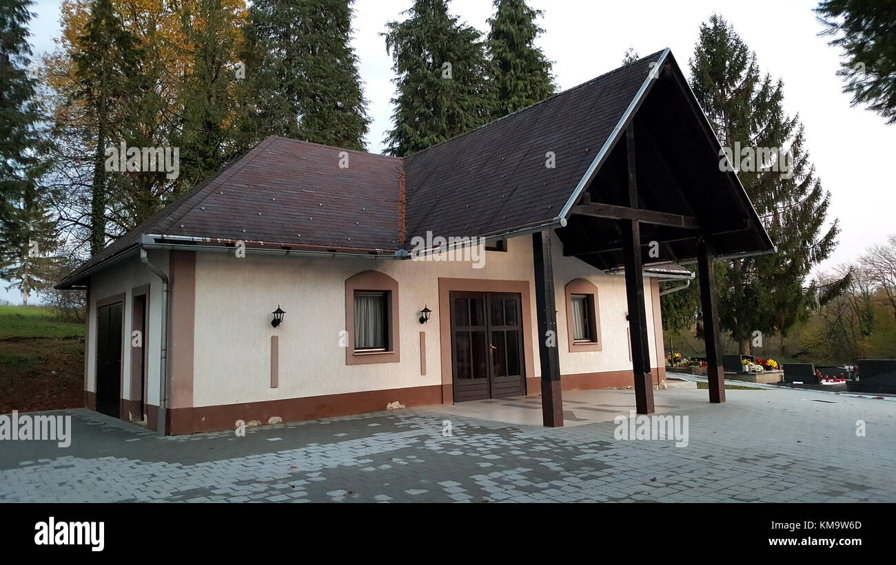 Cemetery mortuary front entrance with large doors, two windows, lights ...