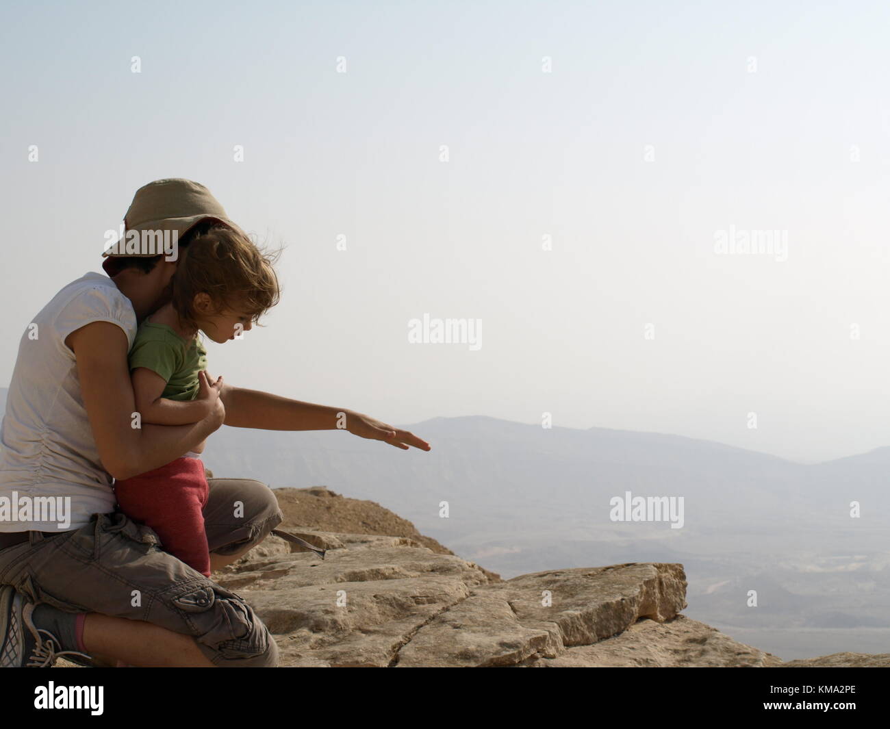 mother and child taking picture an the top of the cliff at the desert ...