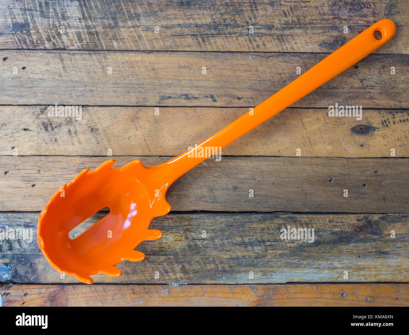 orange plastic spaghetti draining utensil on wood table Stock Photo - Alamy