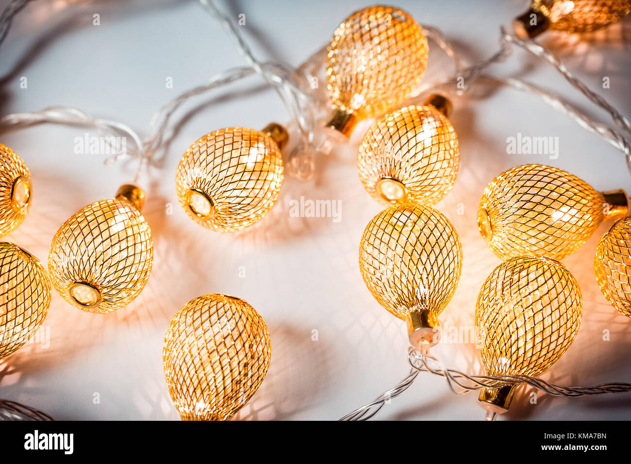 Christmas background with a luminous golden garland on white. A ...