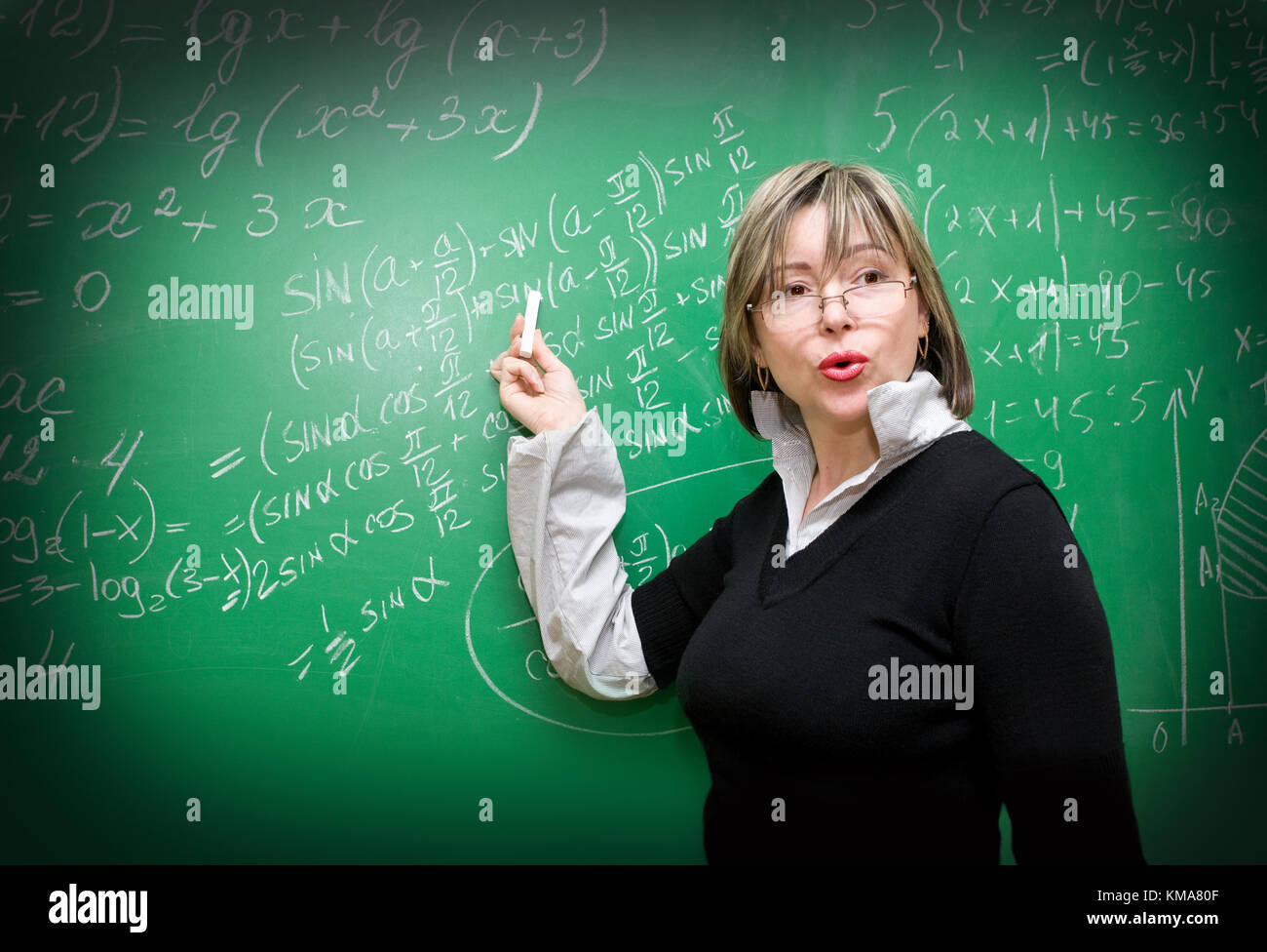 teacher is standing near blackboard in classroom Stock Photo - Alamy