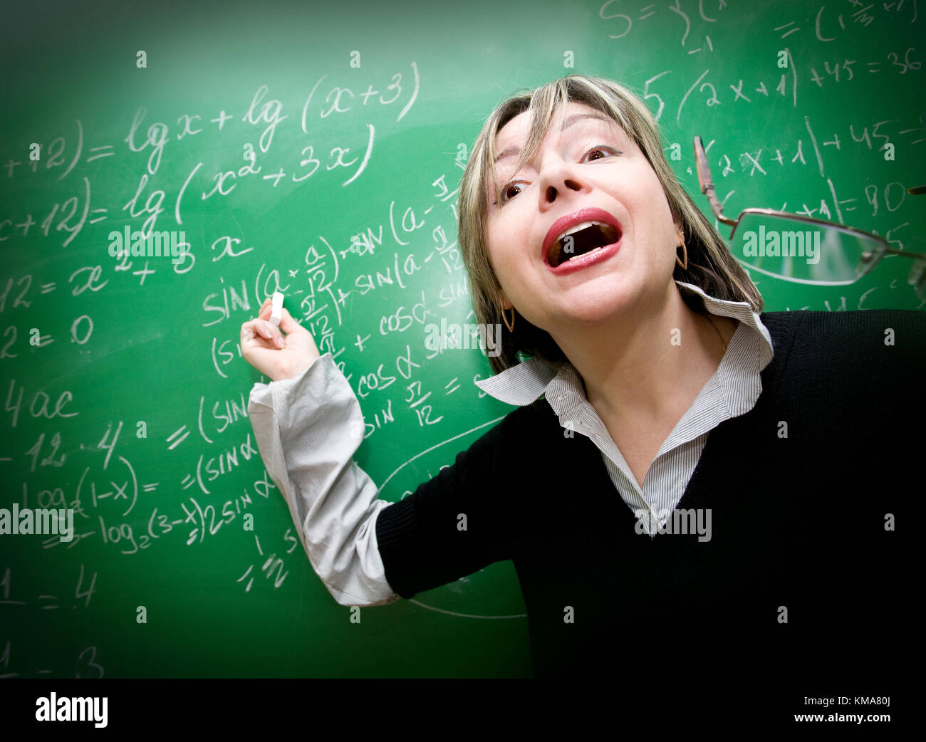 Teacher pointing at blackboard teaching mathematics Stock Photo - Alamy