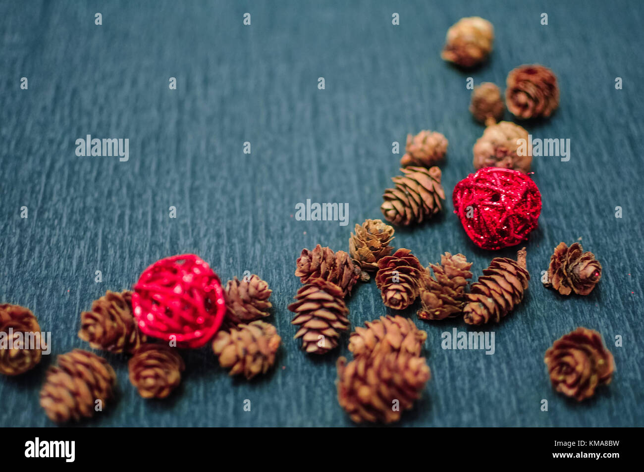 Close up several small cones and red glittering decorative balls lying ...