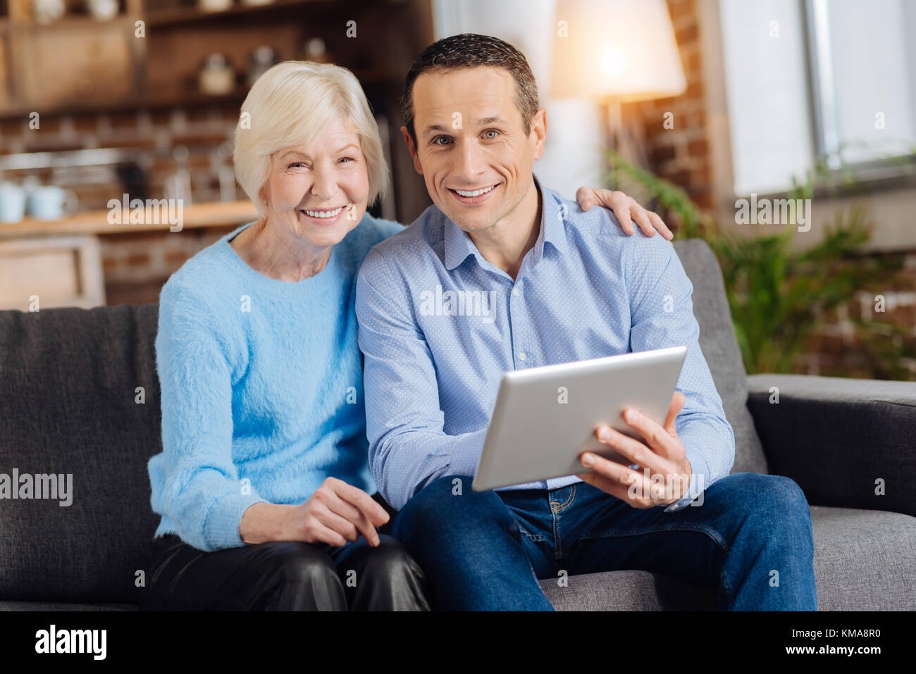 Smiling elderly woman and her son using tablet Stock Photo - Alamy