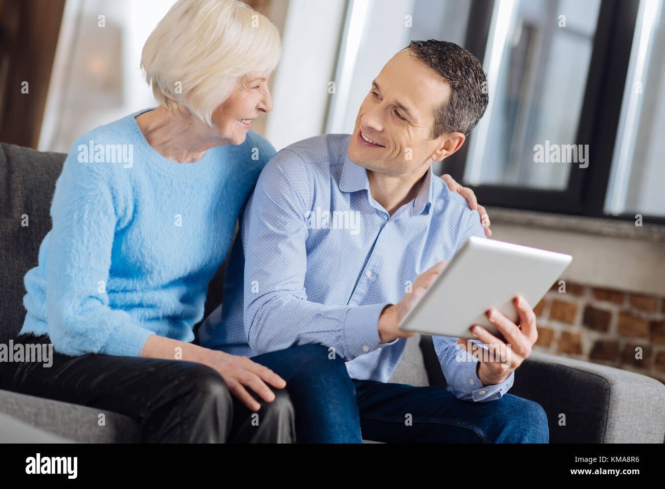 Charming man and his senior mother talking while using tablet Stock ...