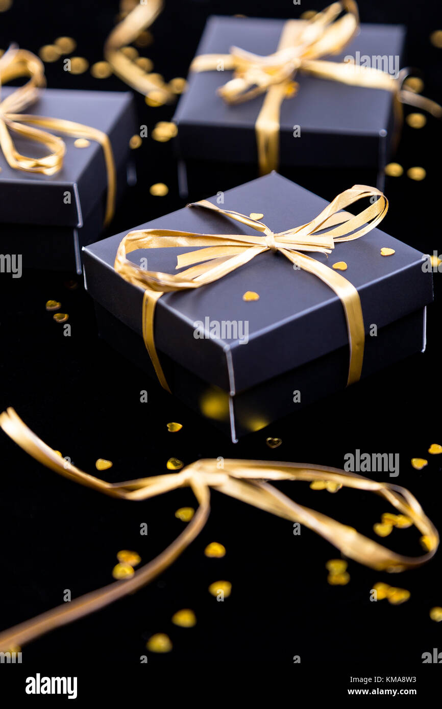 Black gift boxes with gold ribbon on shine background. Close up Stock ...