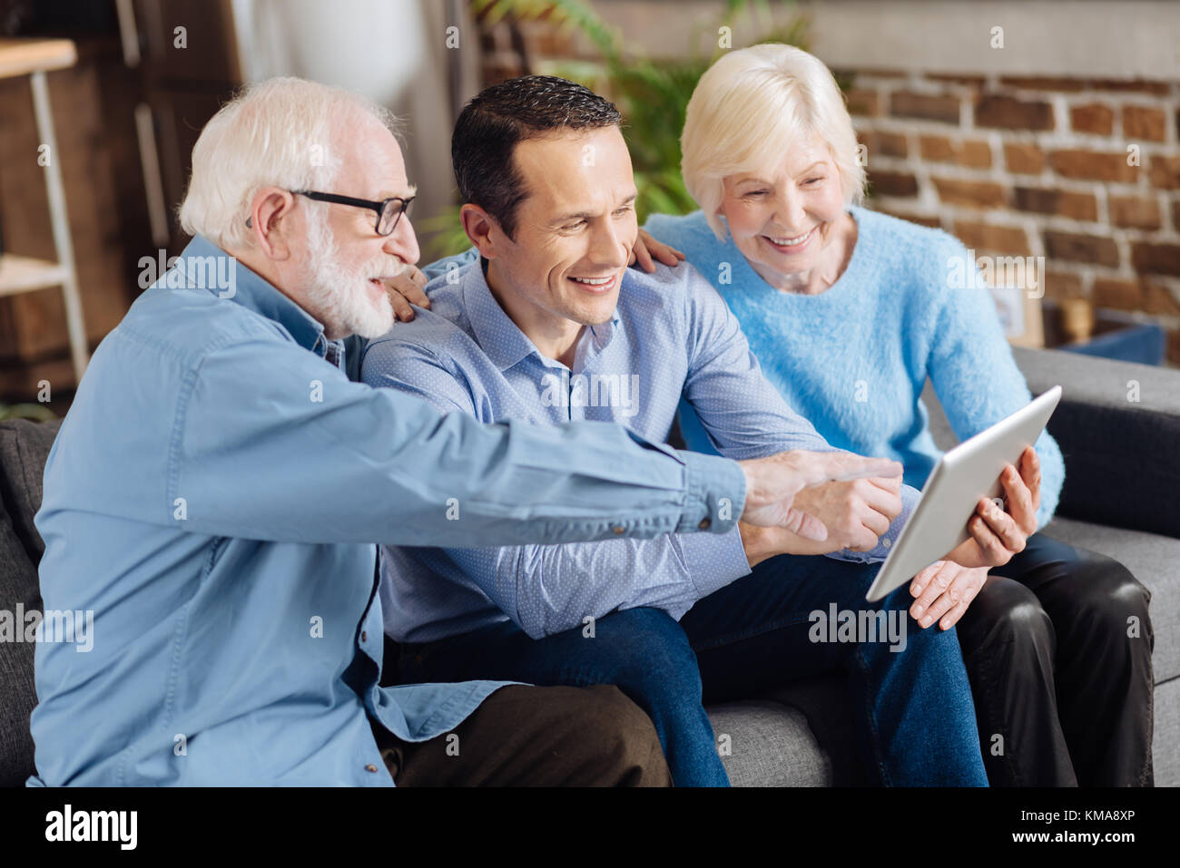 Elderly parents asking their son questions about tablet Stock Photo - Alamy