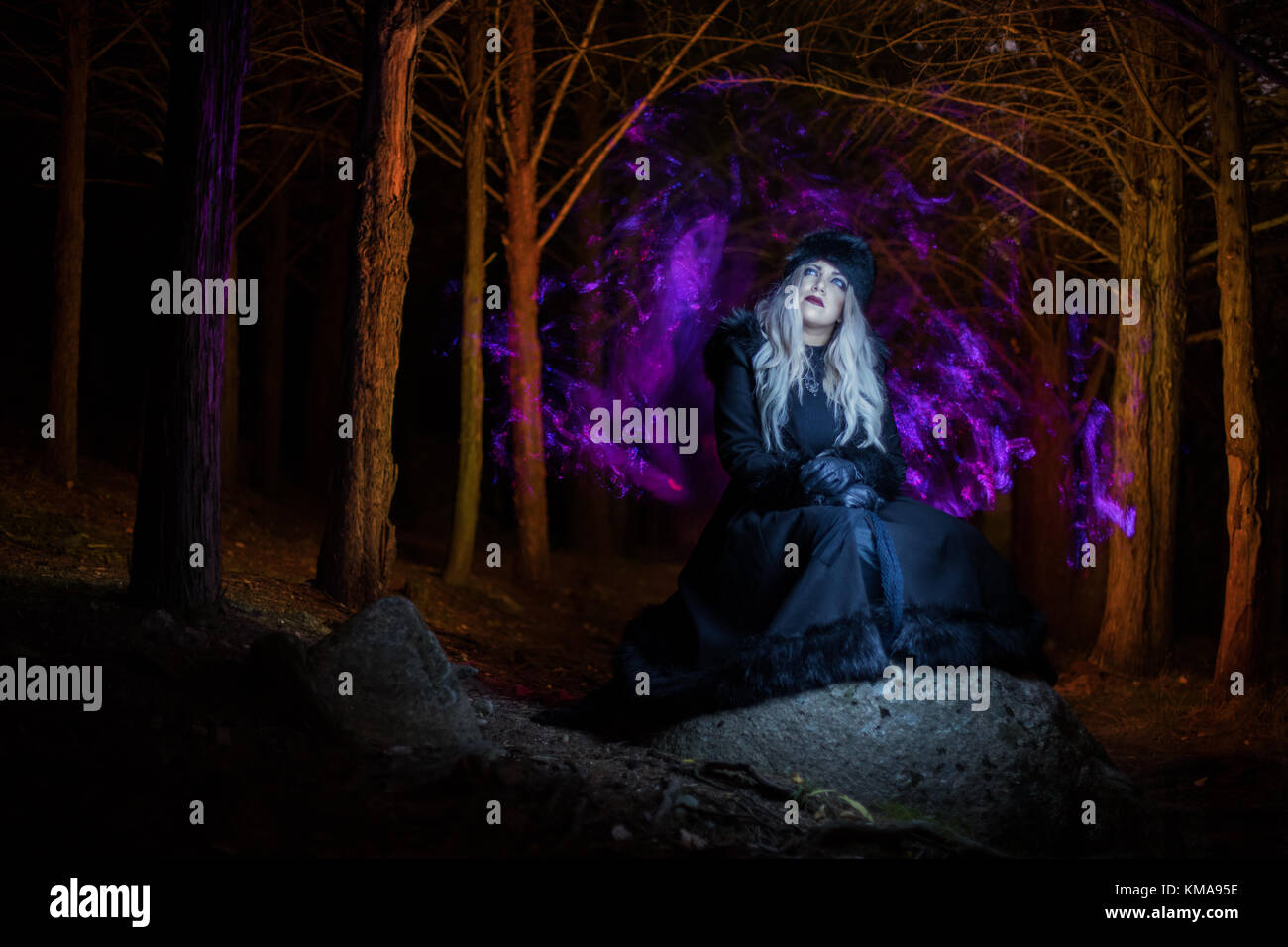 Portrait of a girl in the dark forest with colorful lights around her ...