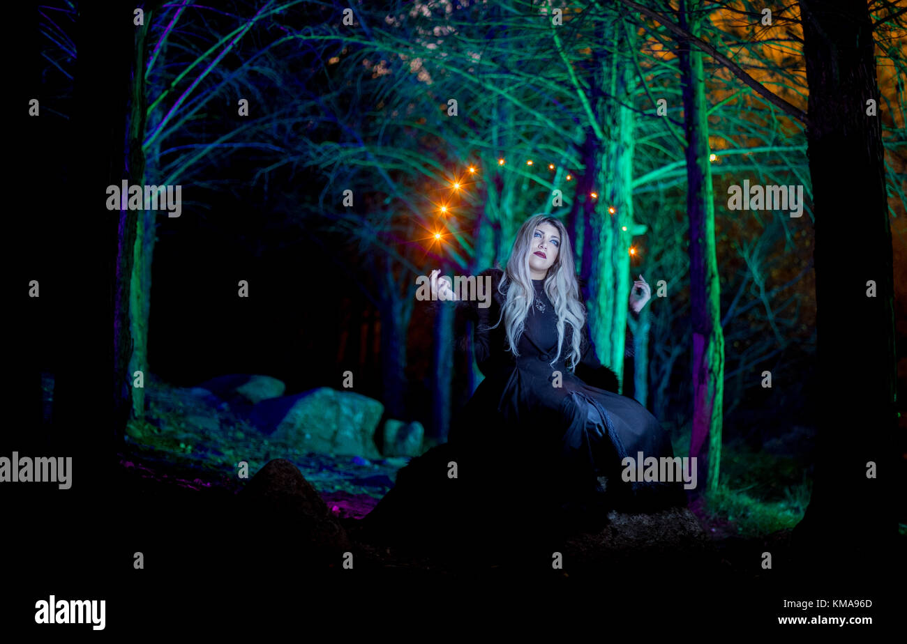 Portrait of a girl in the dark forest with colorful lights around her ...