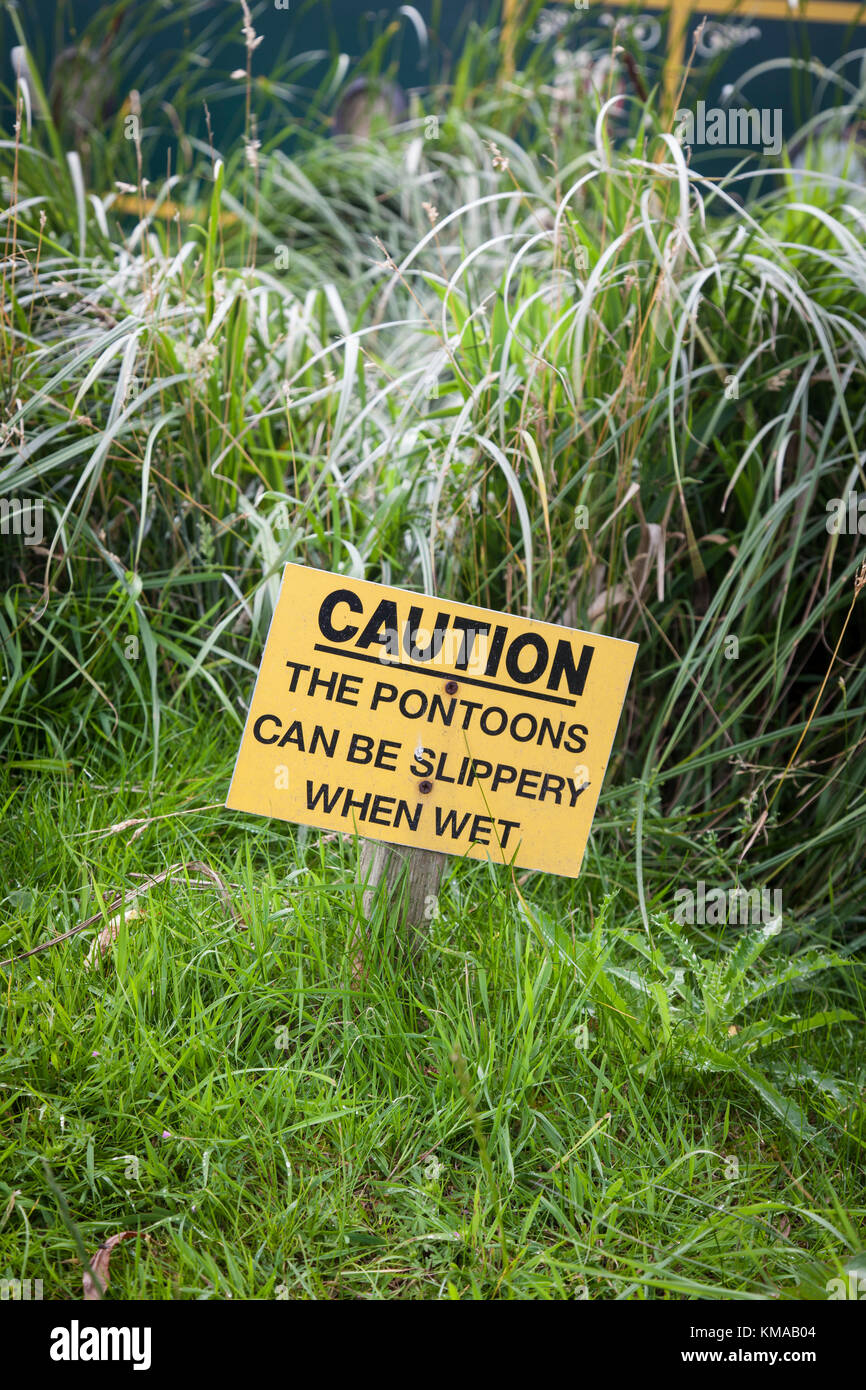 Black on yellow sign at a marina warning that pontoons can be slippery ...