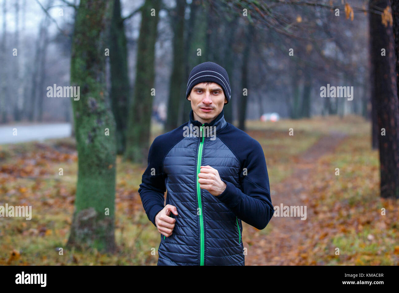 Portrait of young running man in autumn park. Cold season jogging ...