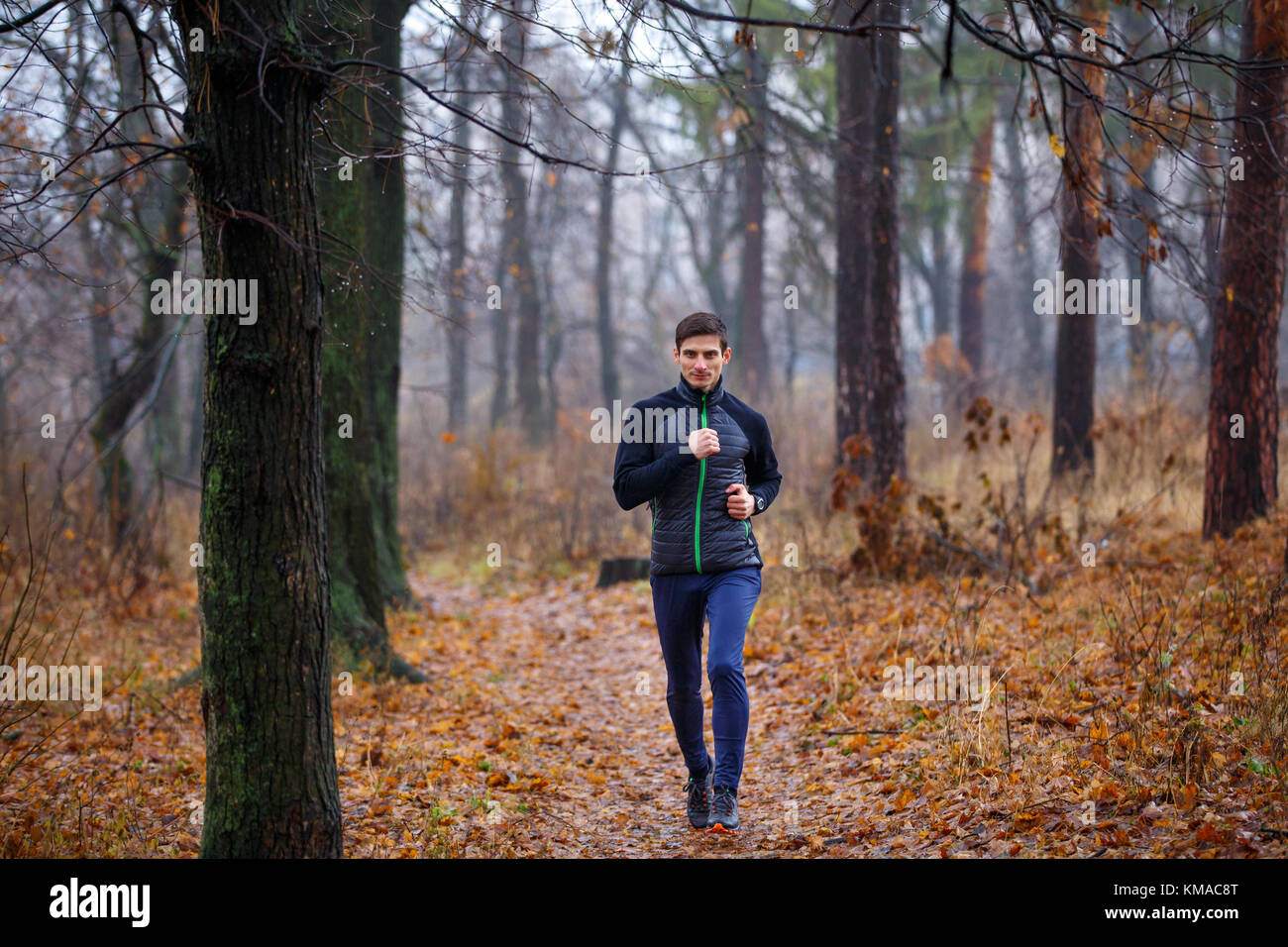Young running man in fall park. Jogging in cold and misty weather Stock ...