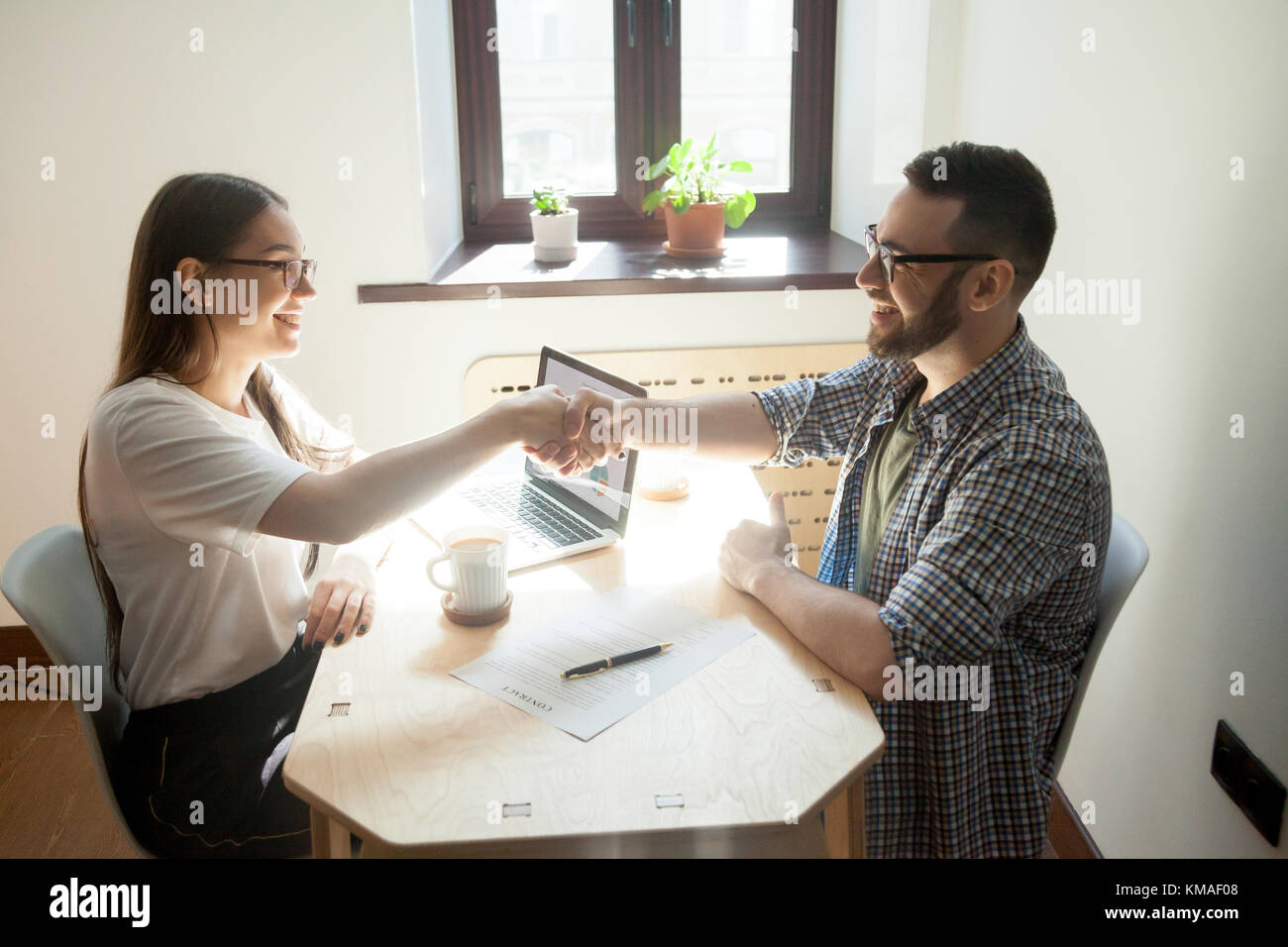 Friendly millennial businessman and businesswoman handshaking over ...
