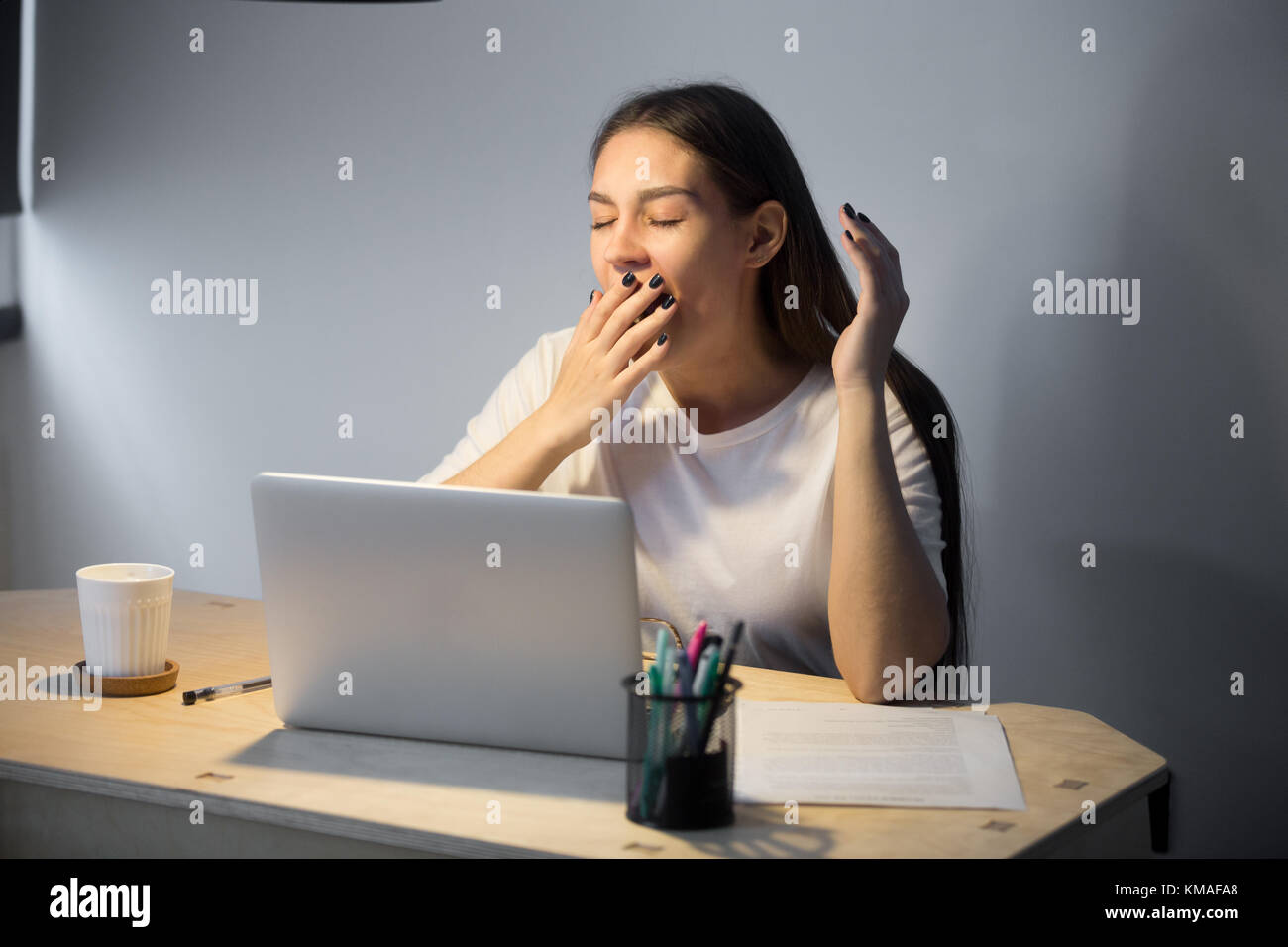 Exhausted millennial businesswoman in casual wear yawning at workplace ...