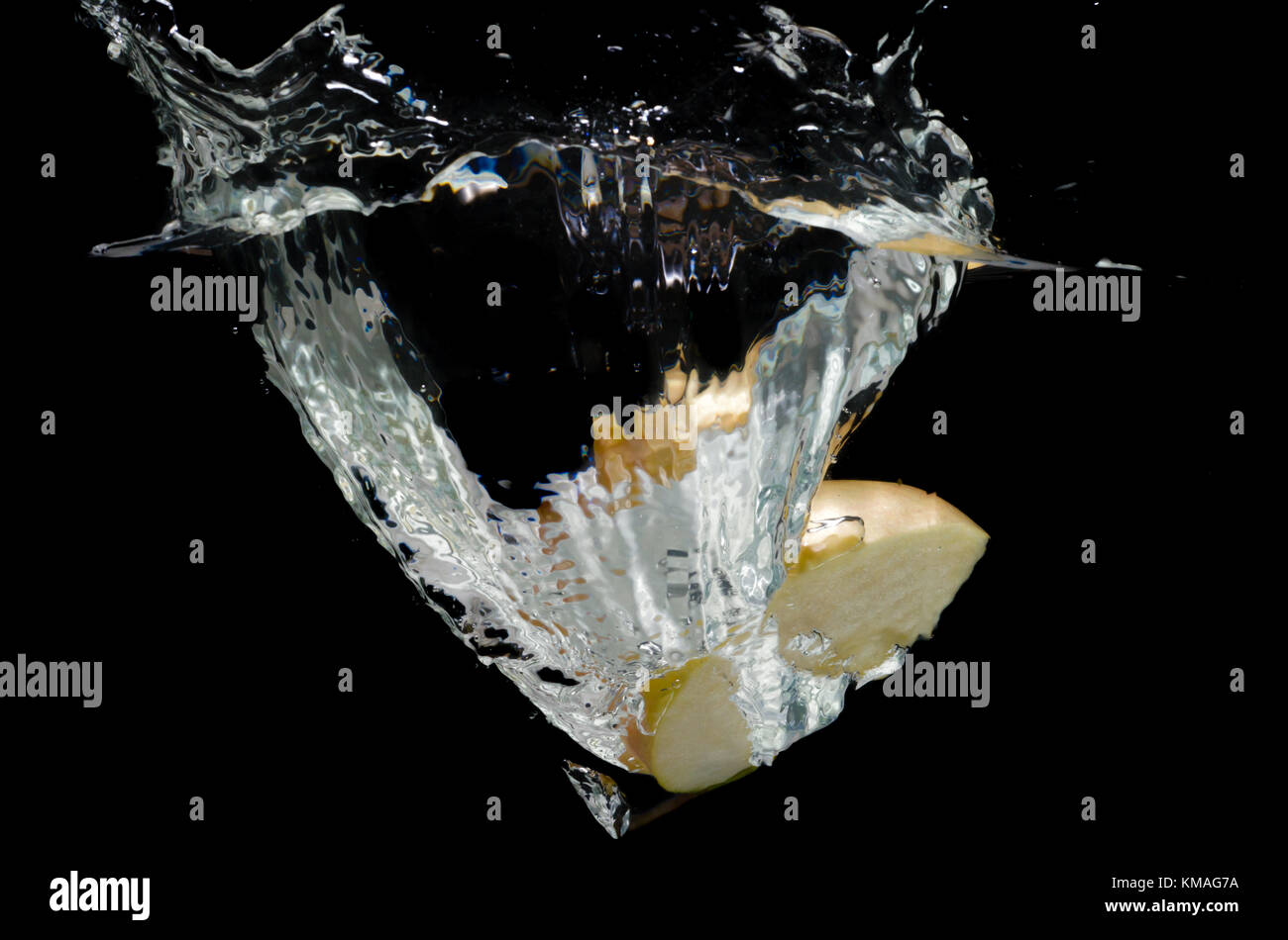 Apple slice falling into splashing water, isolated on black background ...