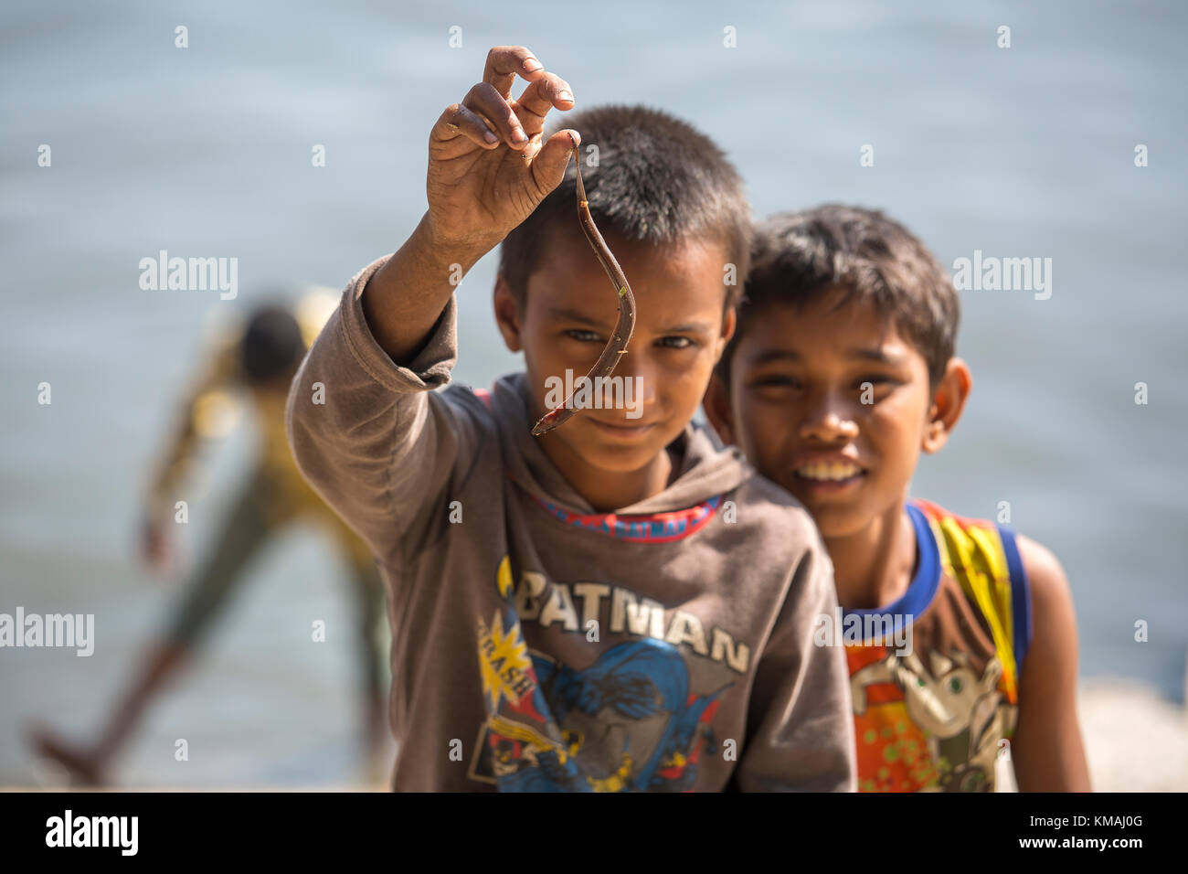 Two kids are playing Baim(Spiny eel) baby fish at a river side ...