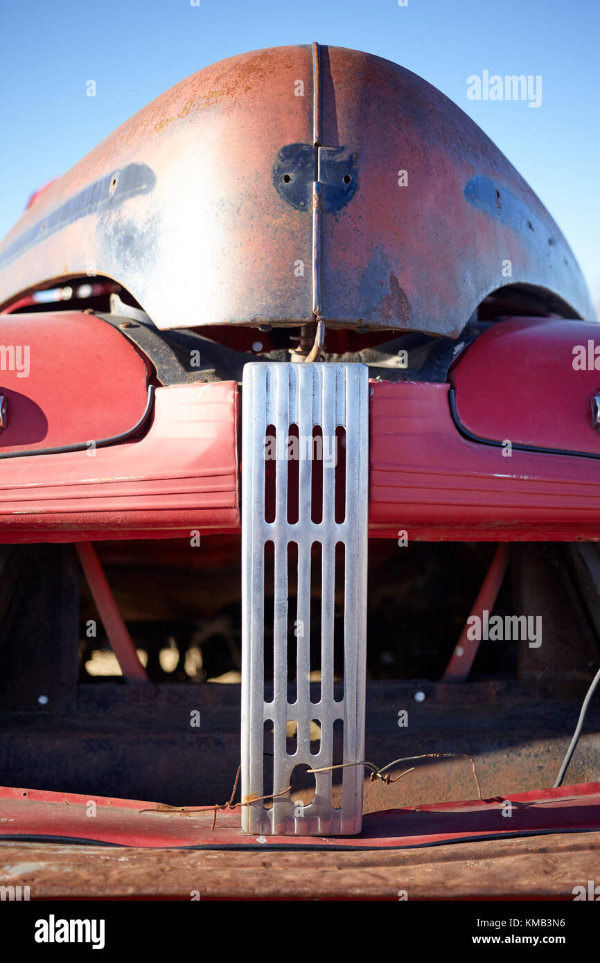 Looking under the hood of a derelict vintage red car with the engine ...
