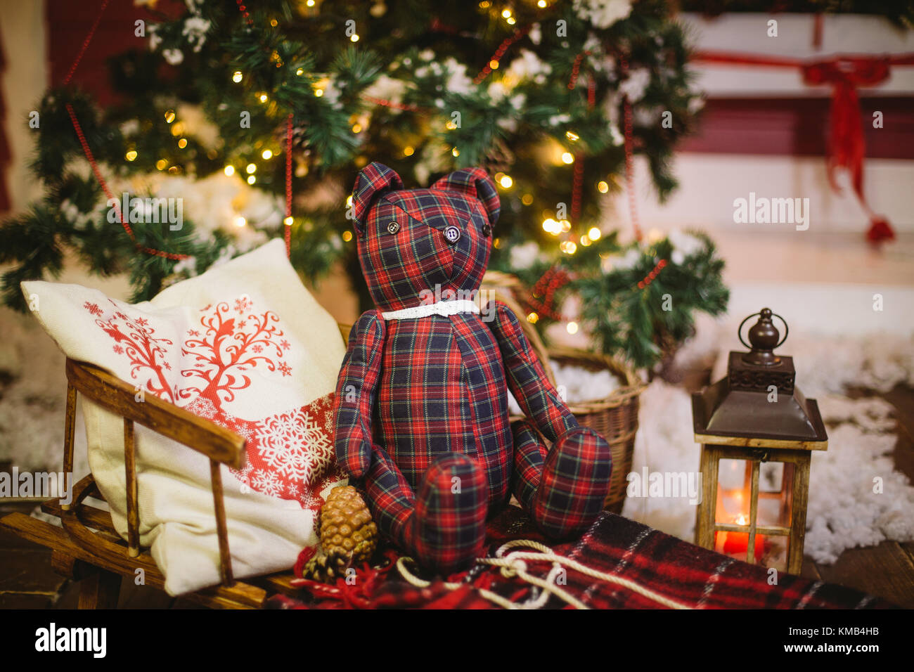 Teddy bear gift sitting under decorated with lights Christmas tree with ...