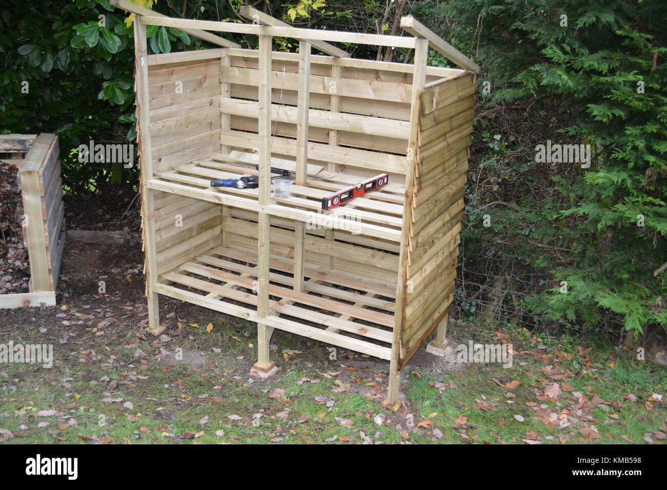 Timber log store under construction in garden with compost heap made ...
