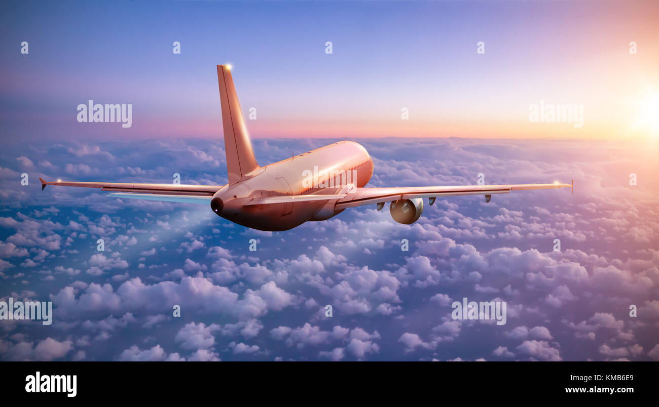 Commercial airplane flying above clouds in dramatic sunset light. High ...