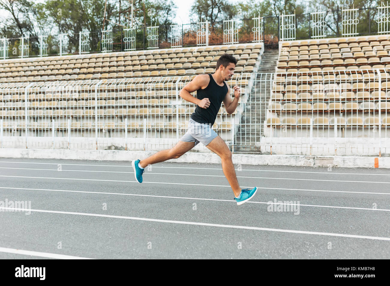 Young athletic man running on the stadium in the morning Stock Photo ...